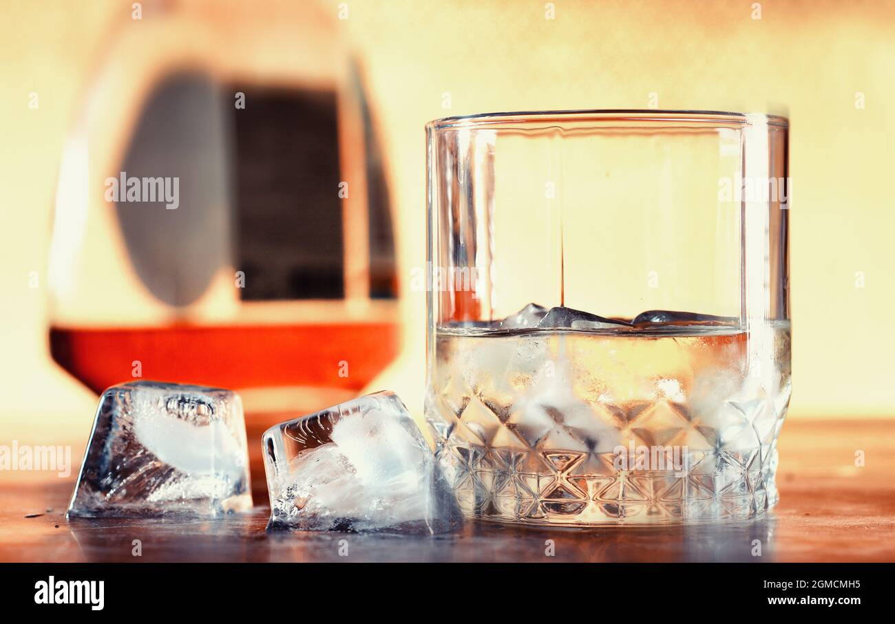 A glass of hard alcohol with ice on a bar counter. Whiskey with soda in ...