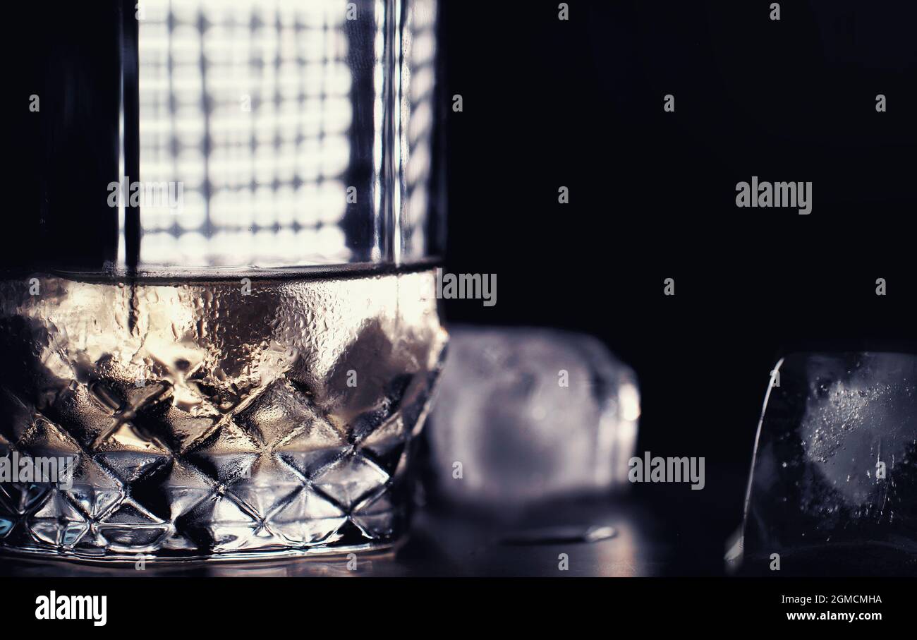 A glass of hard alcohol with ice on a bar counter. Whiskey with soda in ...