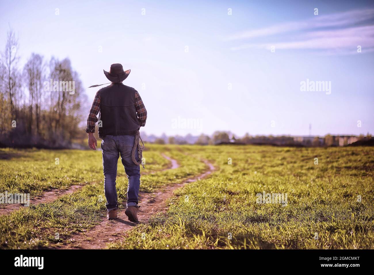 Cowboy in a hat and with a lasso standing in a field at sunset Stock ...