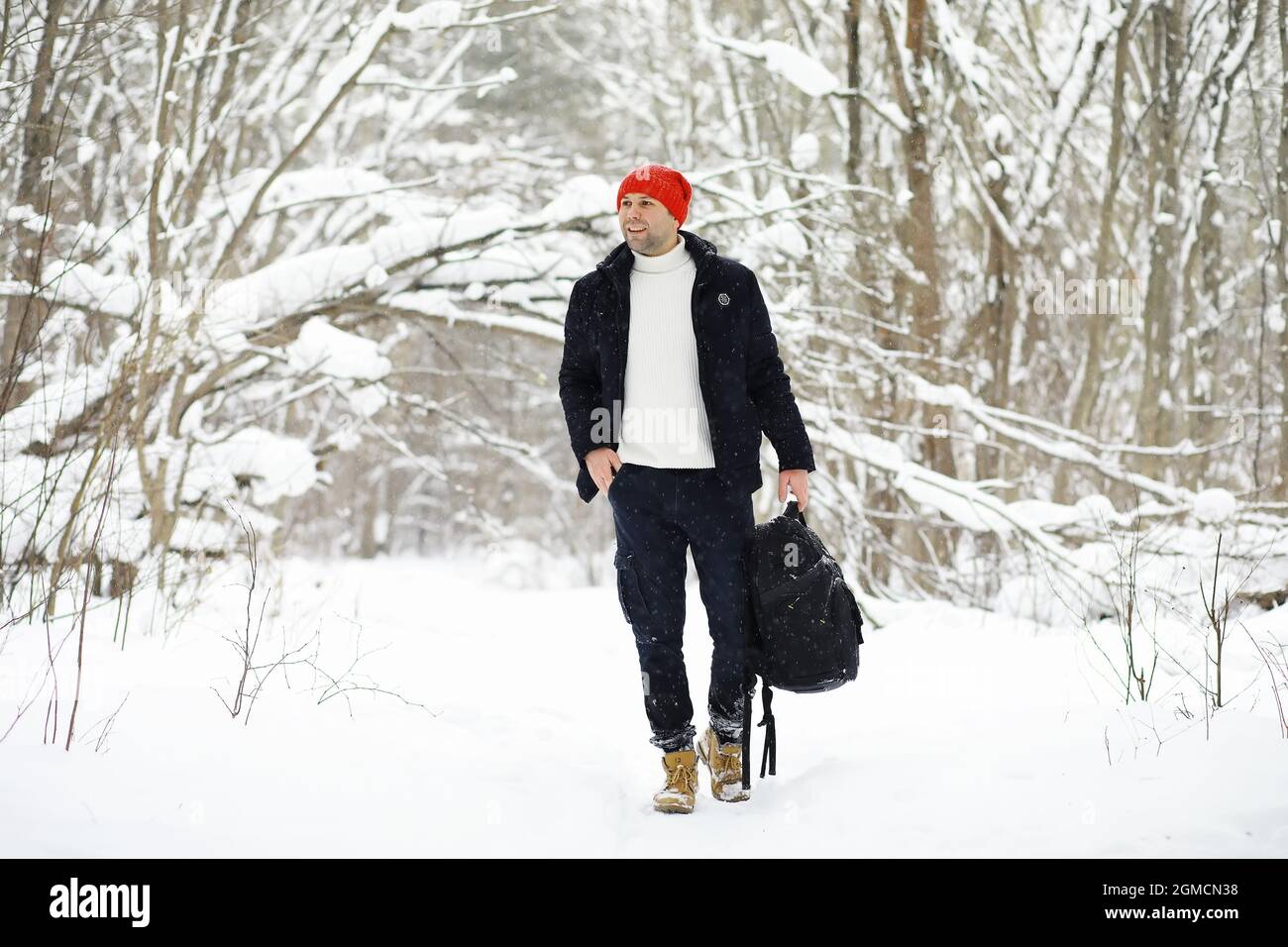 A man in the winter in the forest. A tourist with a backpack goes ...