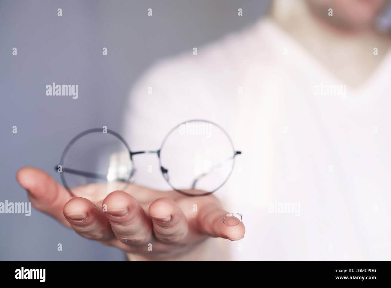 The concept of poor vision. Hold a contact lens and glasses in hand ...