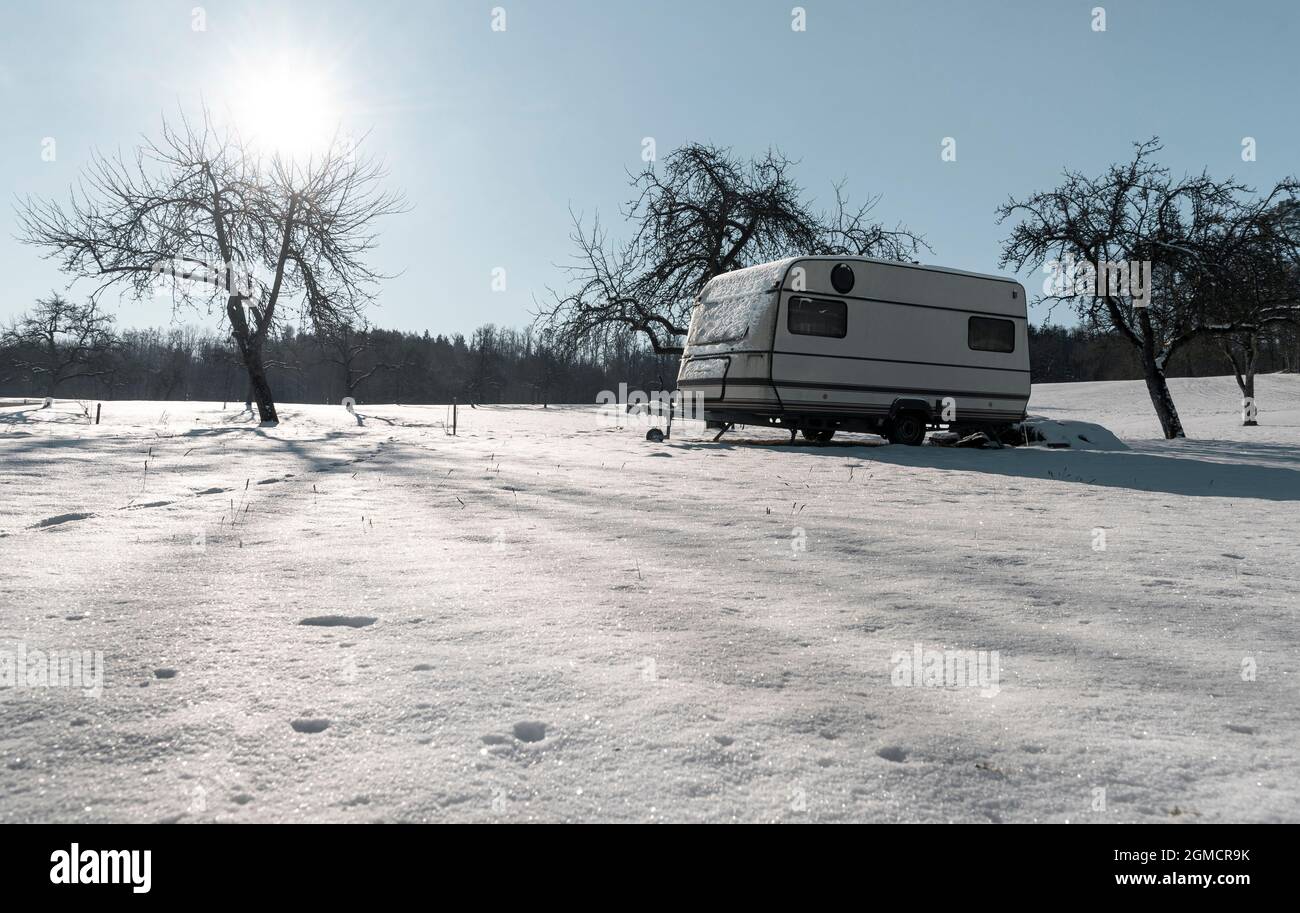 Winter scenery with a camper van parked in a snowy orchard. Sunny ...