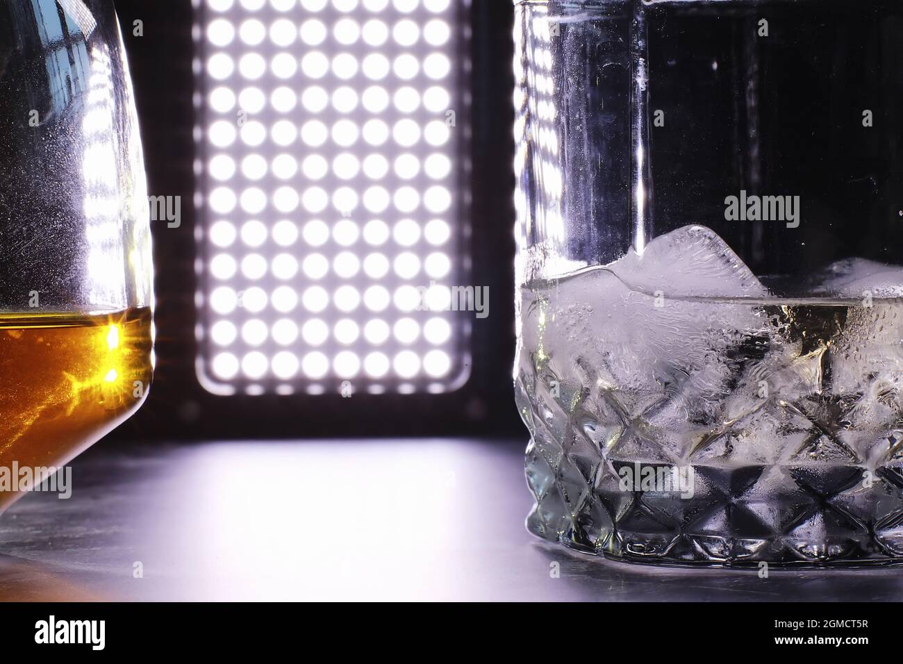 A glass of hard alcohol with ice on a bar counter. Whiskey with soda in ...