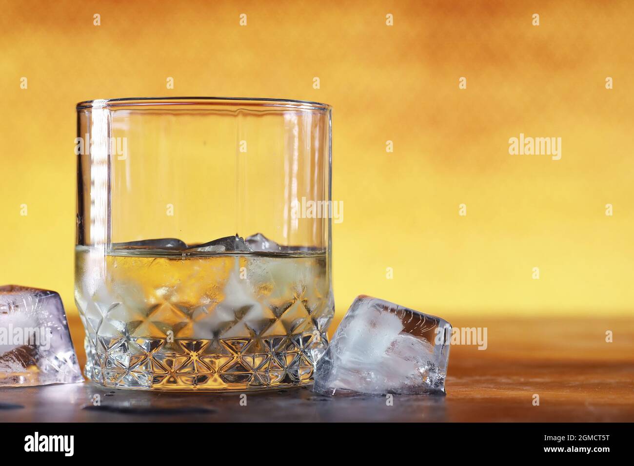 A glass of hard alcohol with ice on a bar counter. Whiskey with soda in ...