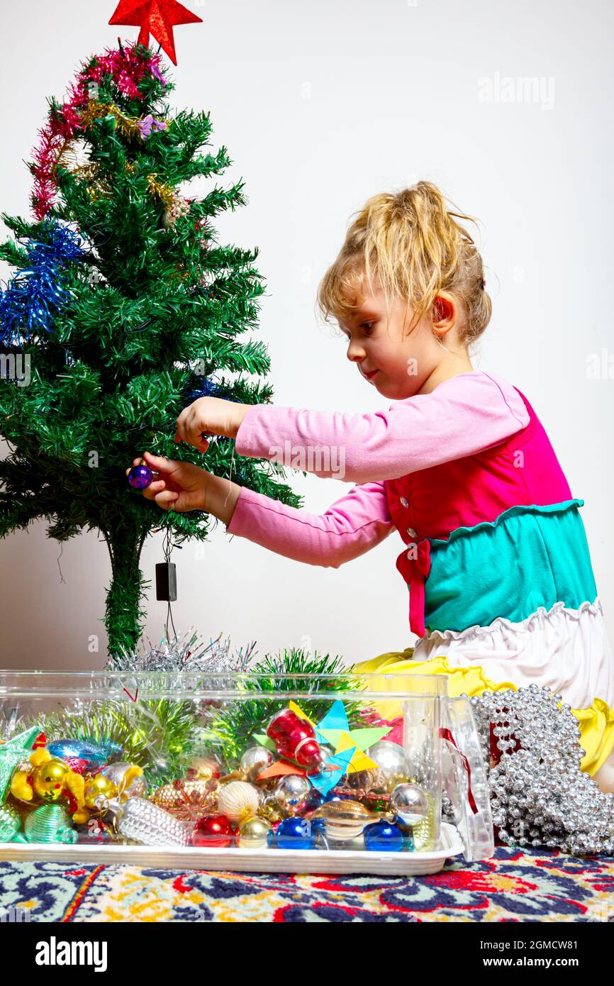 Preschooler female kid, child girl is placing shiny decorative toys ...