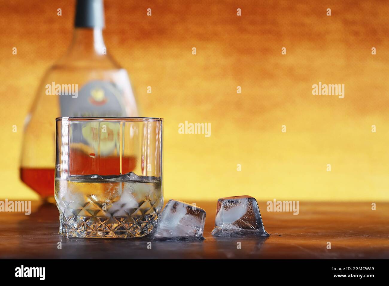 A glass of hard alcohol with ice on a bar counter. Whiskey with soda in ...