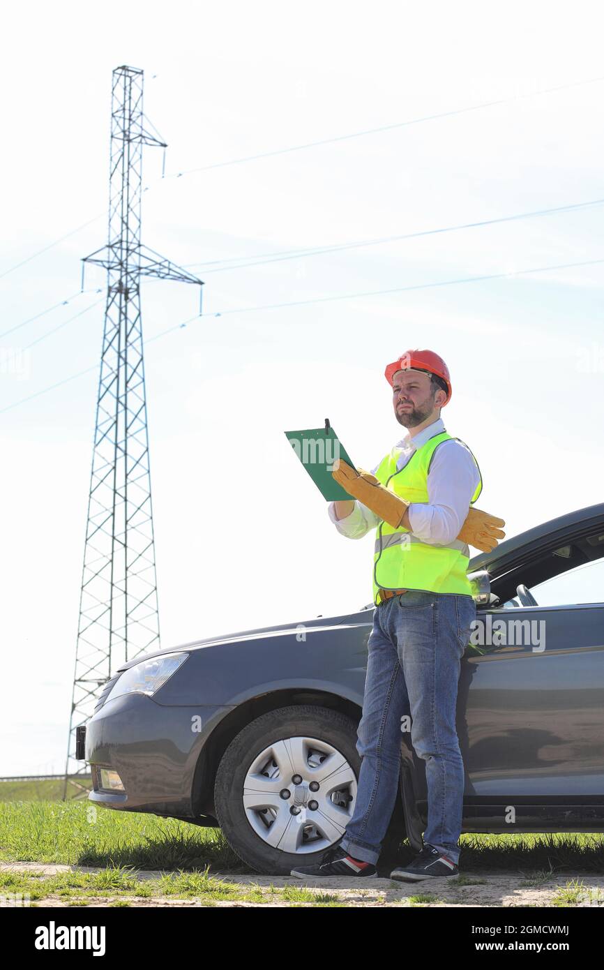 An electrician in the fields near the power transmission line. The ...