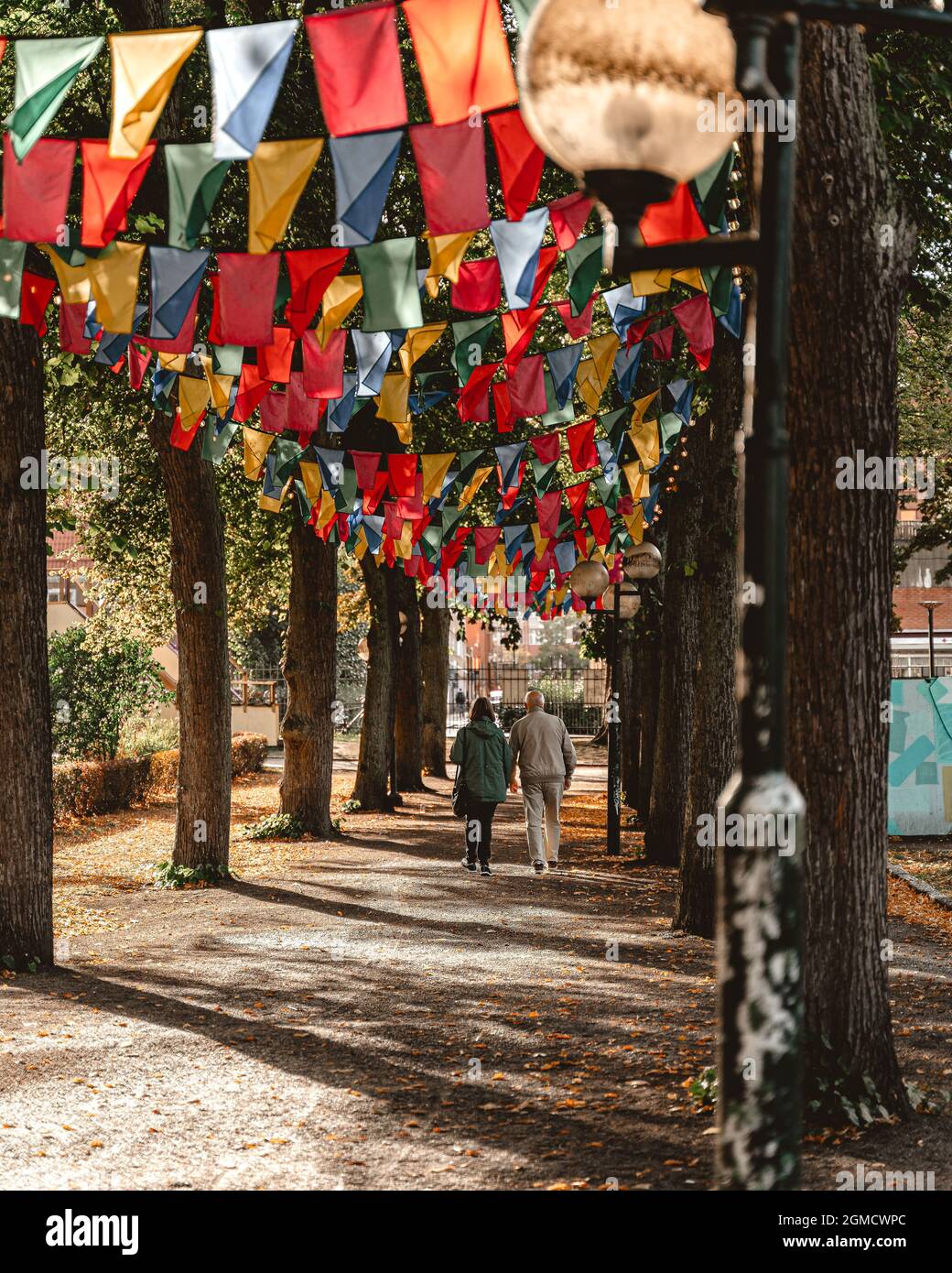 Vertical shot of a couple walking in the park decorated with small ...