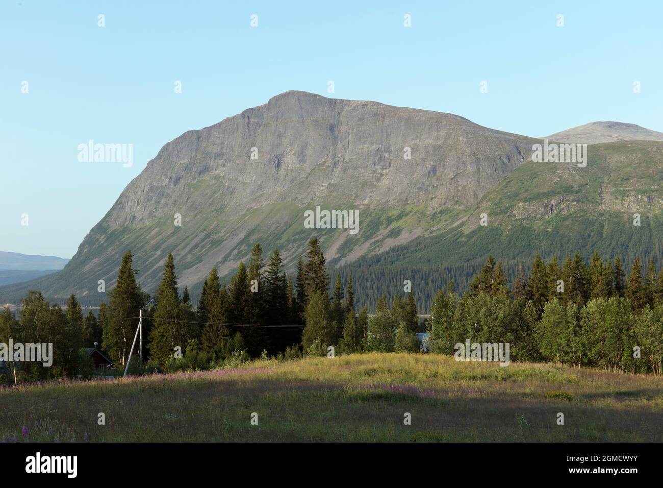 Huge cliff, rock beyond forest and lake. Medows this side, morning ...