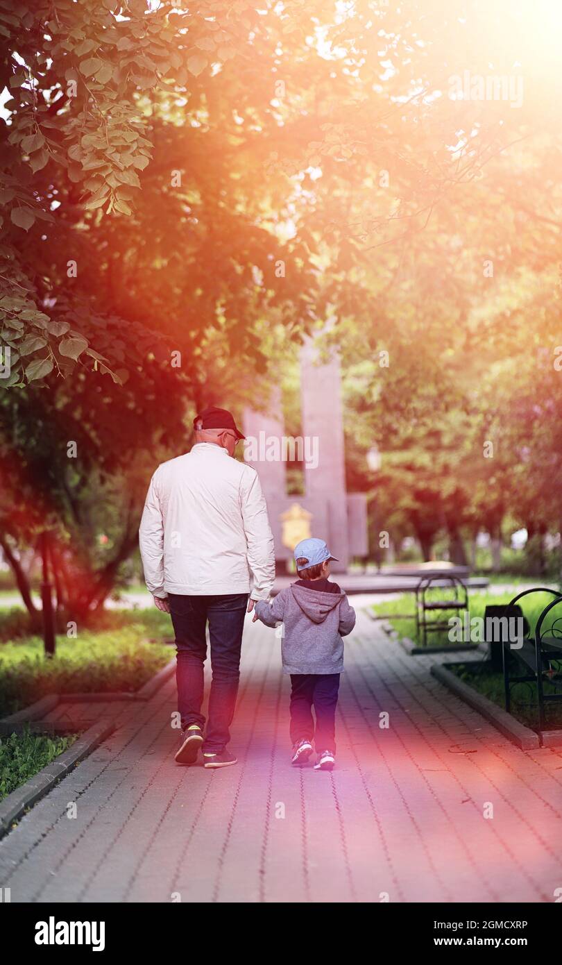 Grandpa is walking with her grandson in a spring park. Grandson and ...