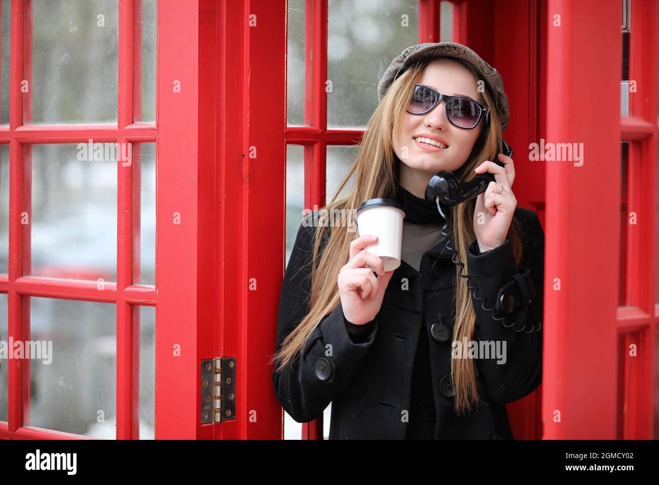 Beautiful young girl in a phone booth. The girl is talking on the phone ...