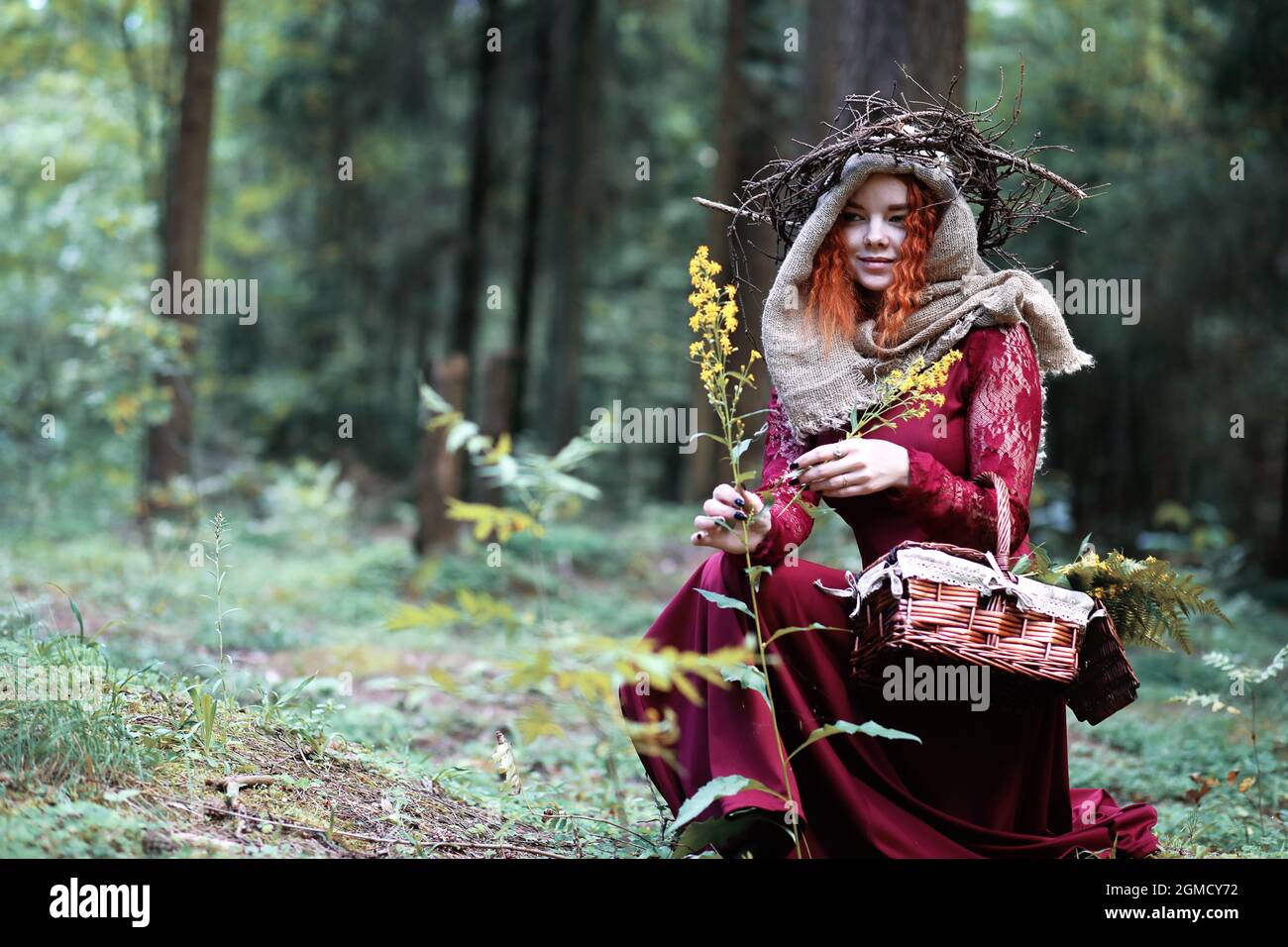 The red-haired witch holds a ritual with a crystal ball in the forest ...