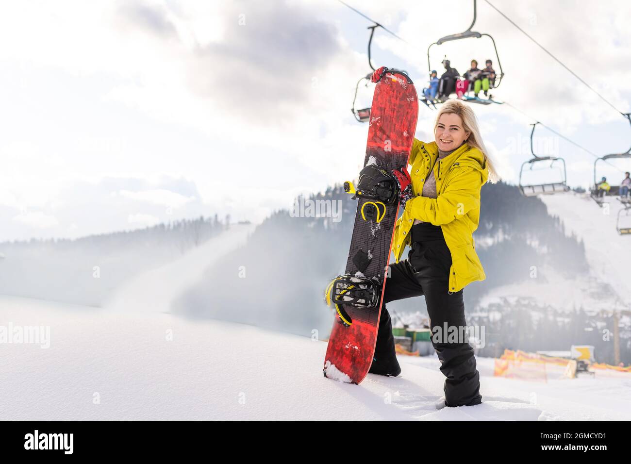 Young woman holding snowboard at winter resort Stock Photo - Alamy