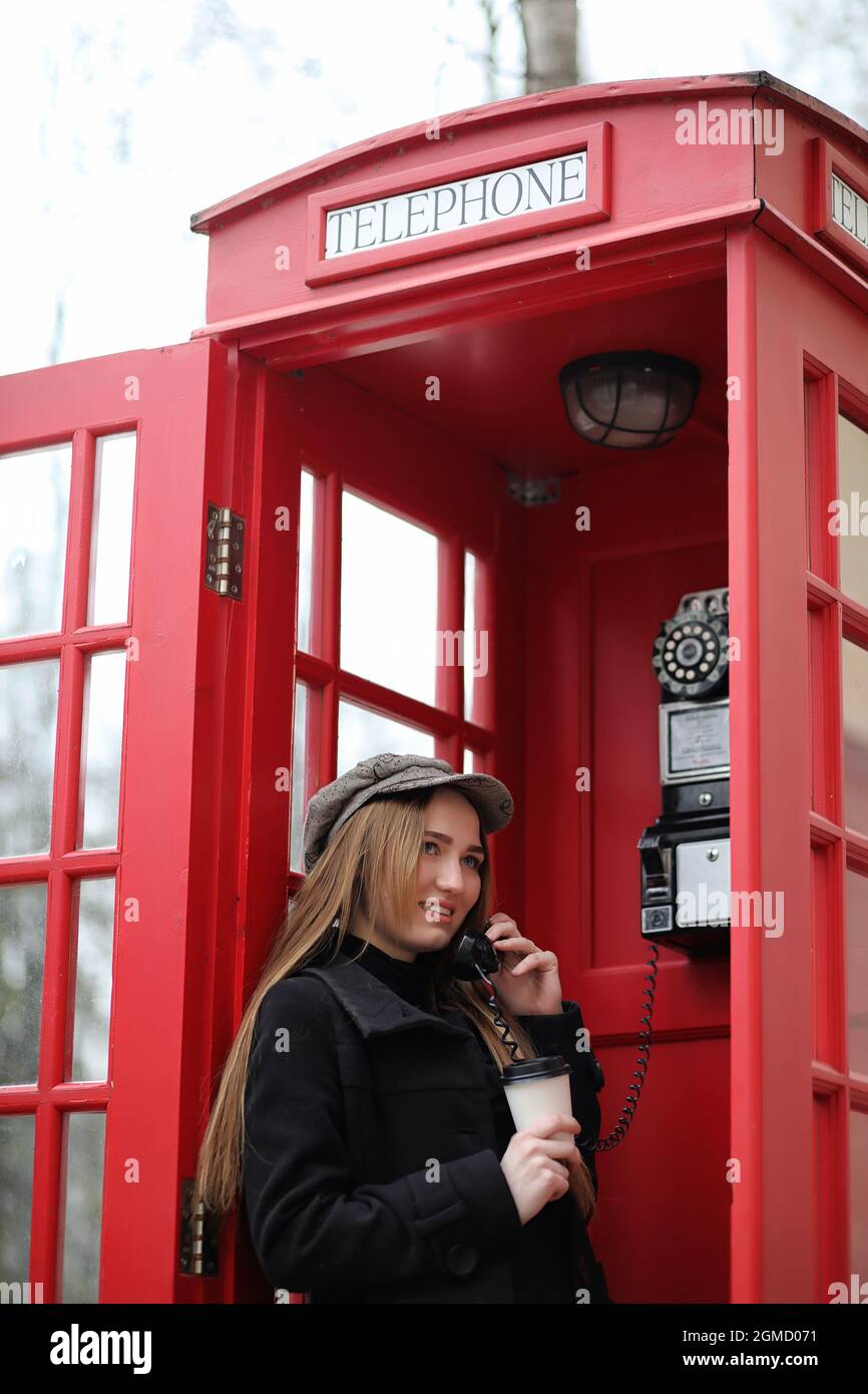 Beautiful young girl in a phone booth. The girl is talking on the phone ...