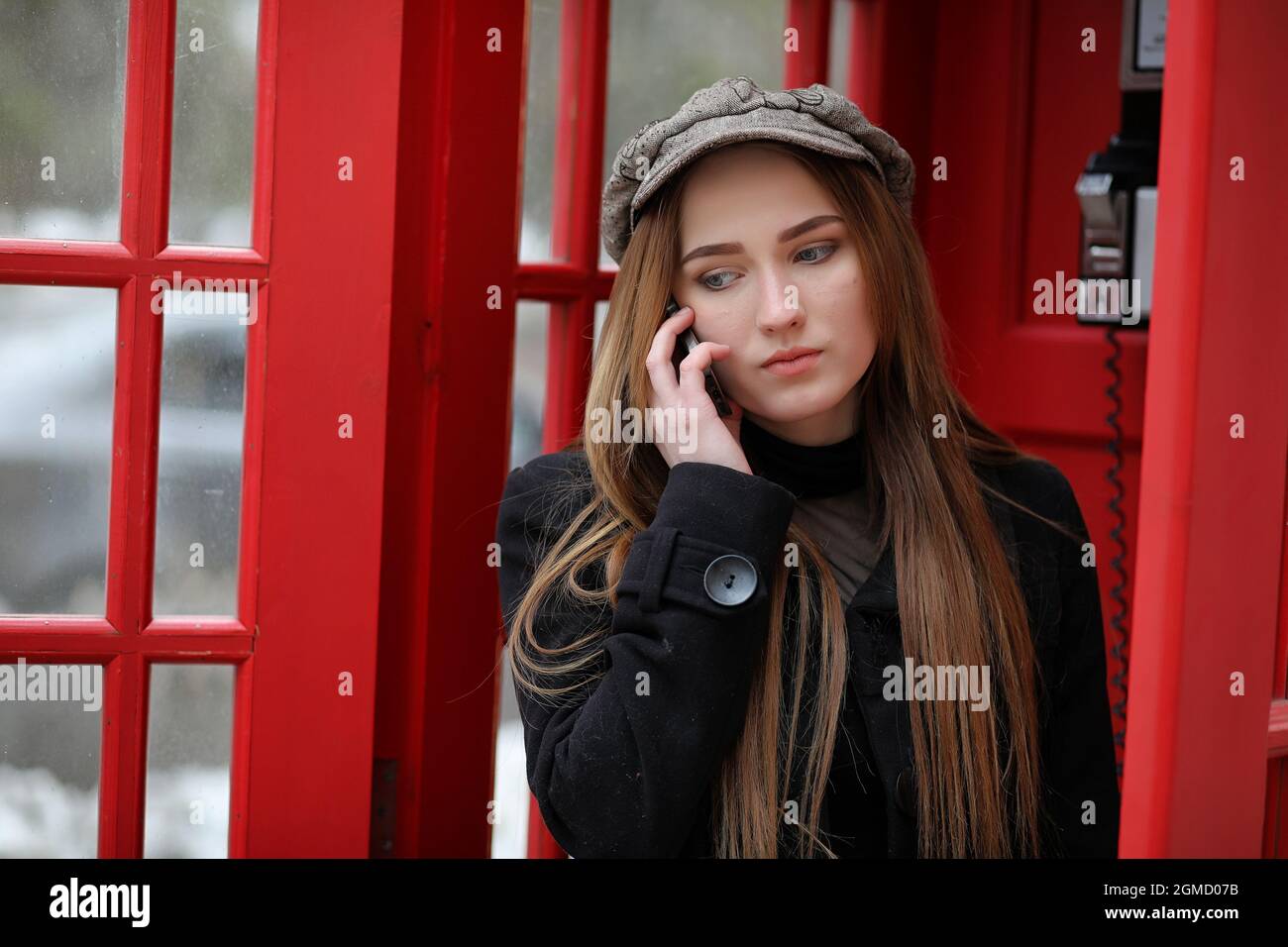 Beautiful young girl in a phone booth. The girl is talking on the phone ...