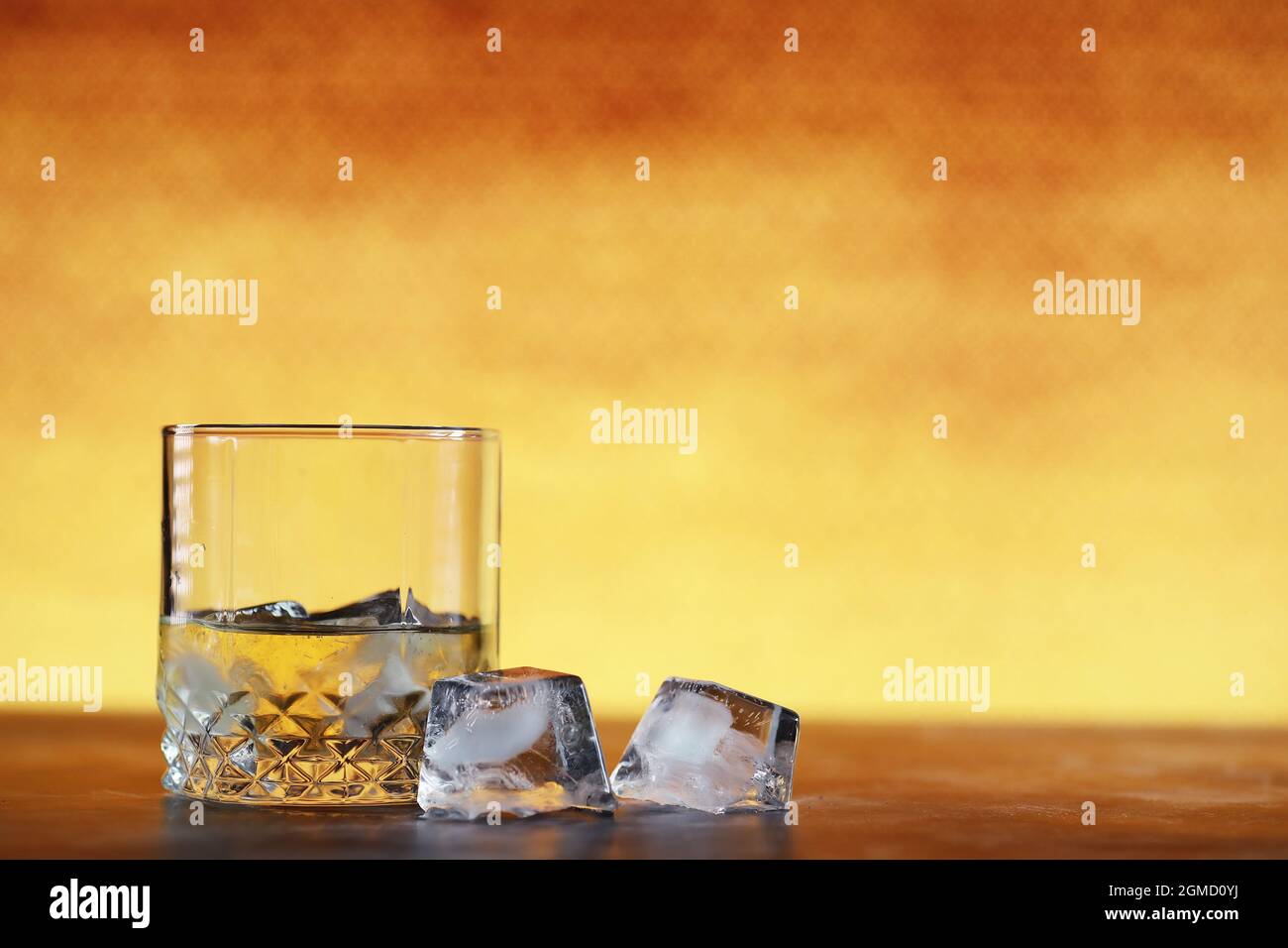 A glass of hard alcohol with ice on a bar counter. Whiskey with soda in ...