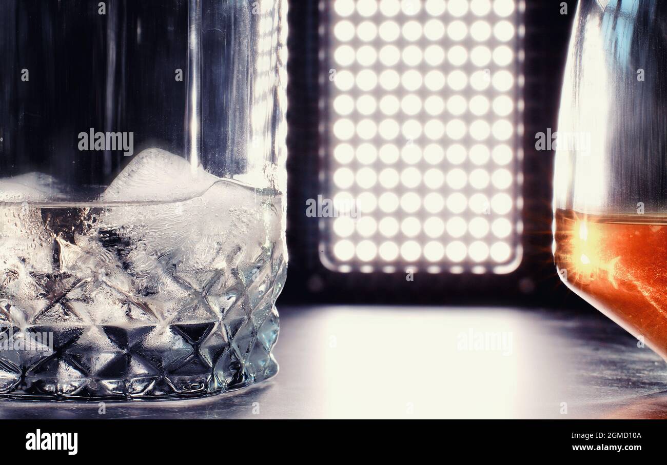 A glass of hard alcohol with ice on a bar counter. Whiskey with soda in ...