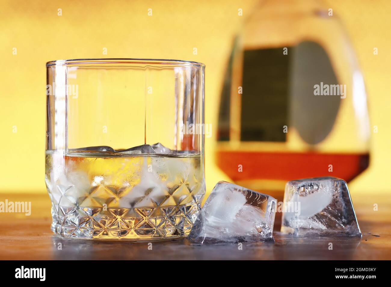 A glass of hard alcohol with ice on a bar counter. Whiskey with soda in ...