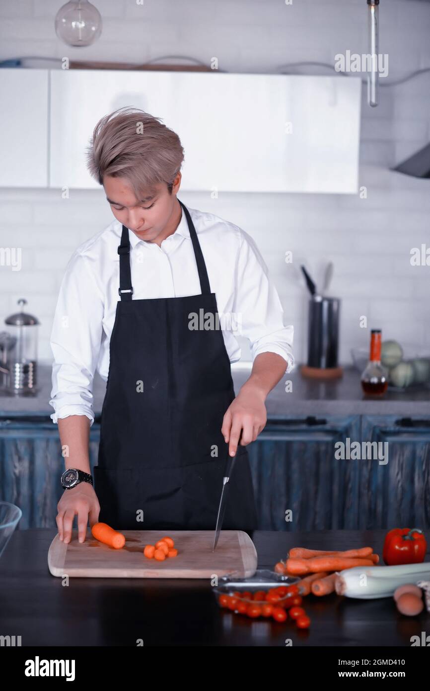 A young Asian cook in the kitchen prepares food in a cook suit Stock ...