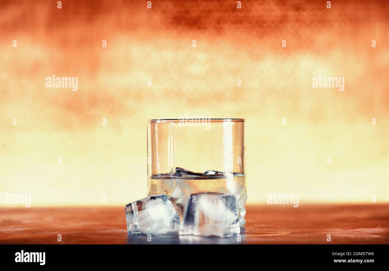 A glass of hard alcohol with ice on a bar counter. Whiskey with soda in ...