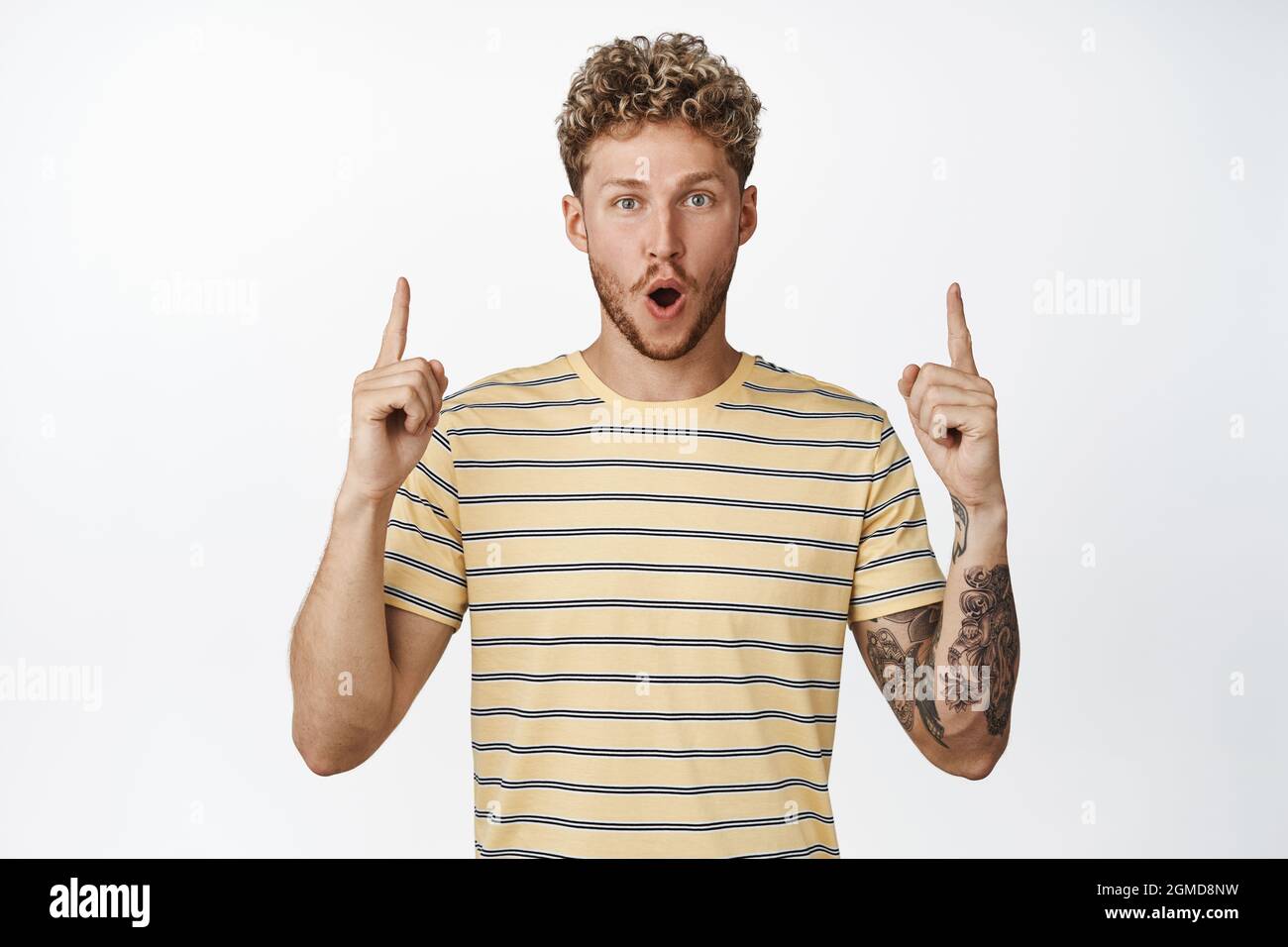 Image of surprised happy guy pointing fingers up at promotional text ...
