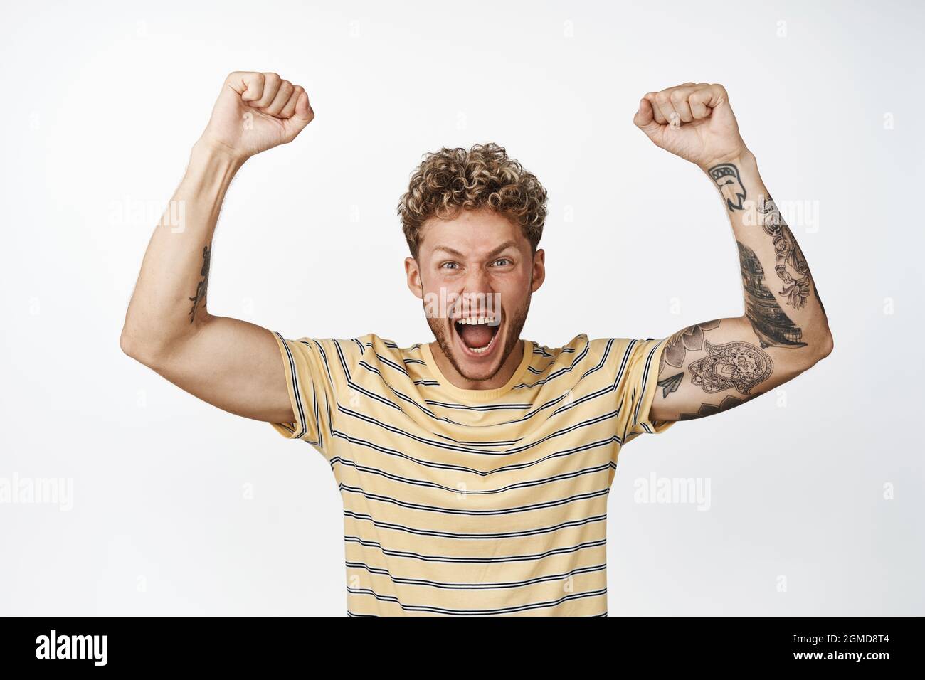Excited blond guy rooting, winning prize and raising hands up to ...