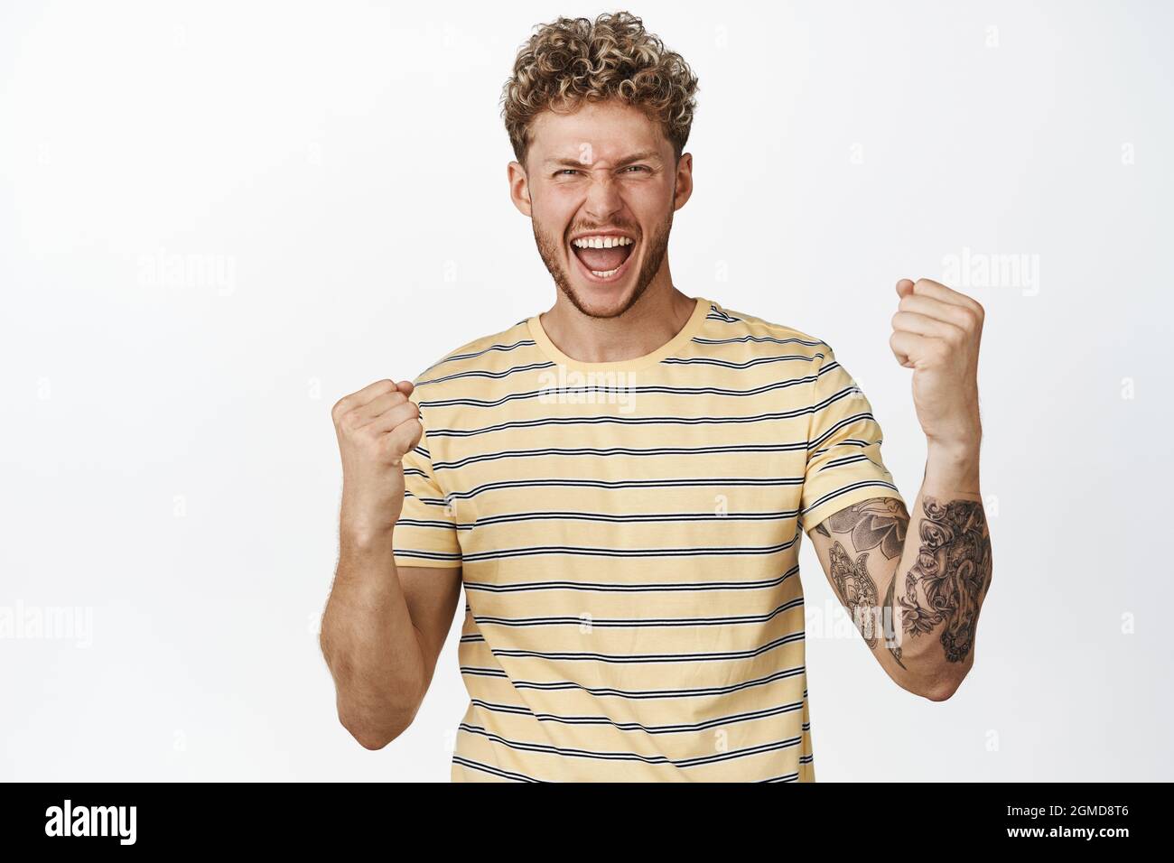 Excited blond young man, cheering, celebrating victory, screaming with ...