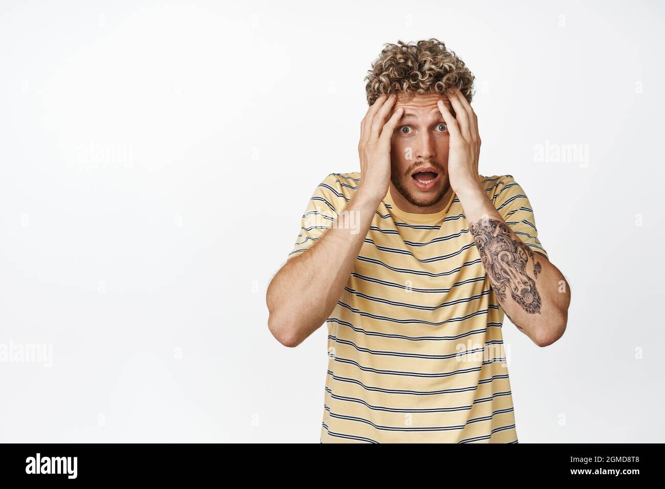 Shocked blond guy hold his head in panic, looking anxious and alarmed ...