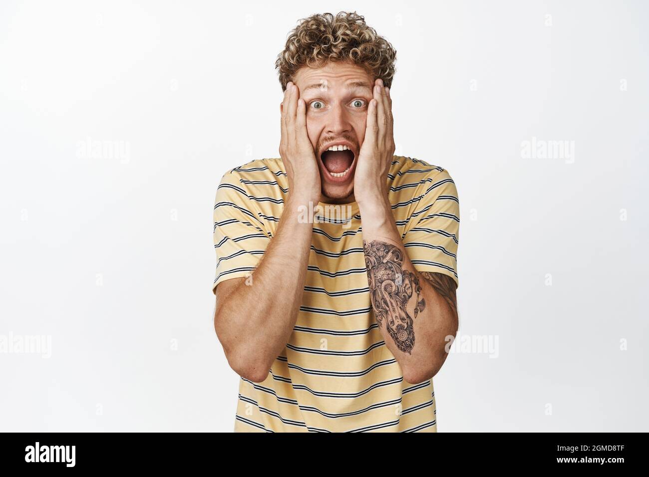 Excited young man screams in disbelief, staring surprised at his prize ...