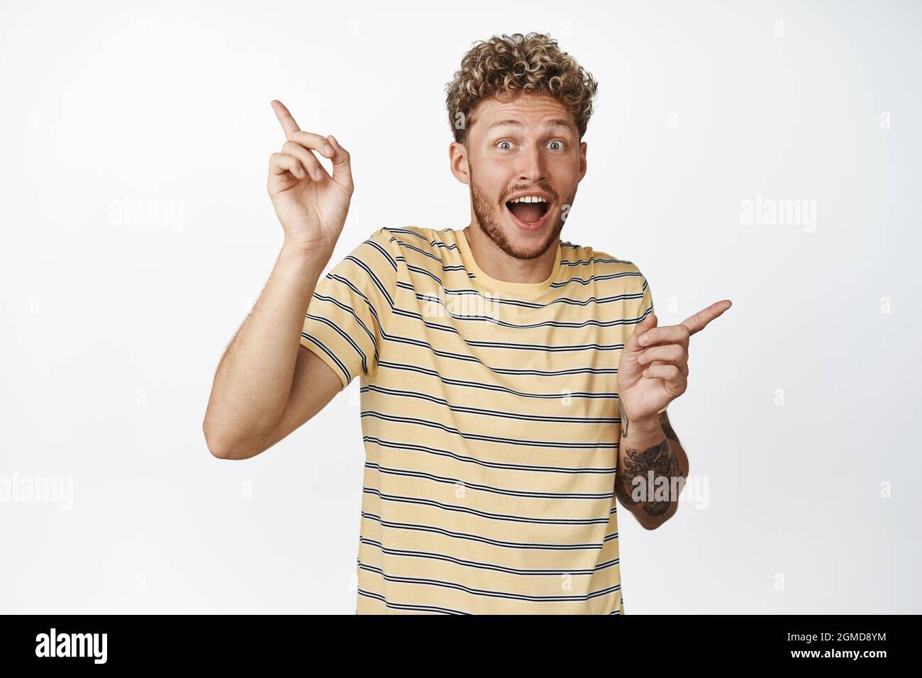 Happy blond young man pointing fingers sideways, showing left and right ...