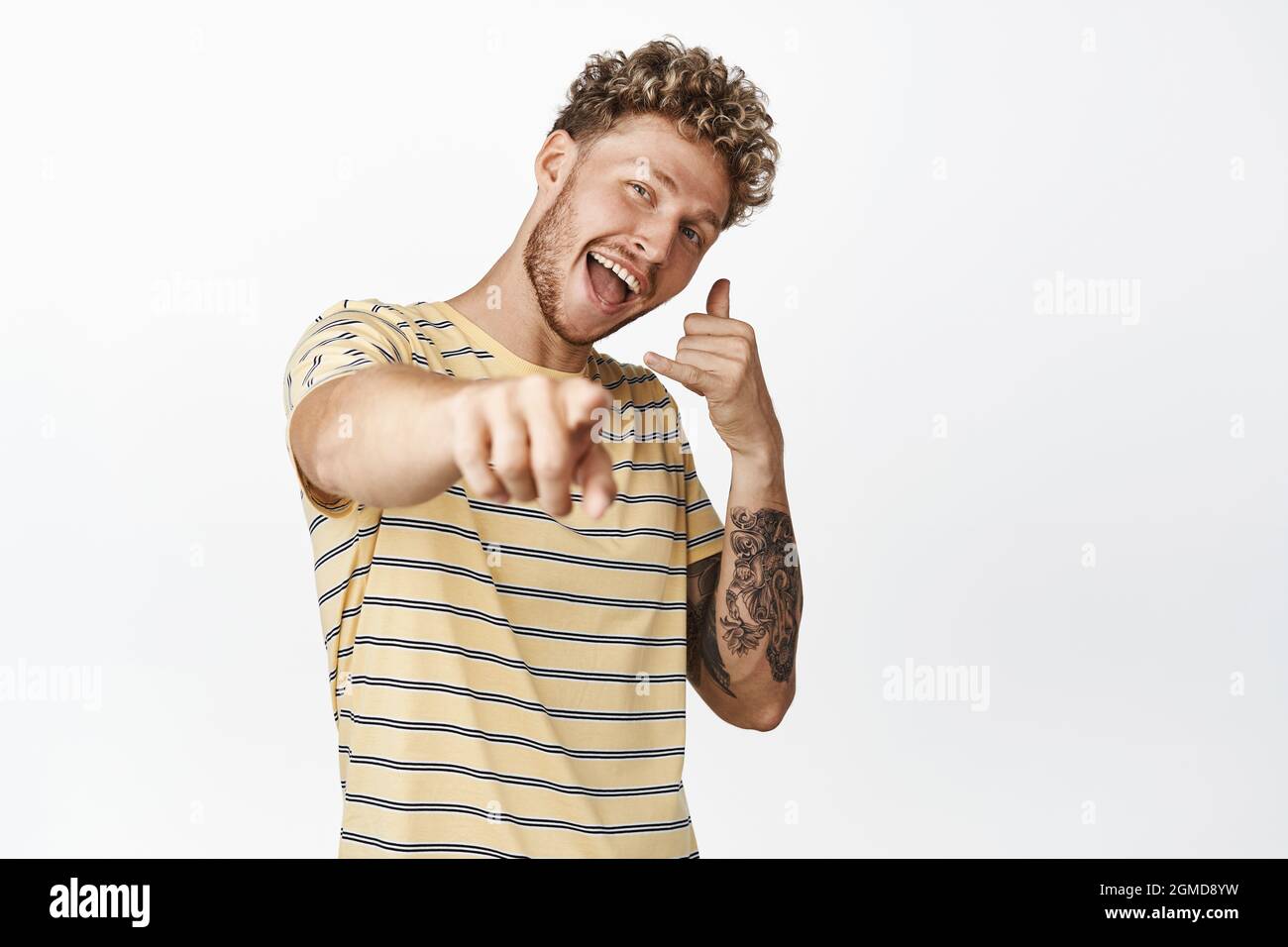 Cheerful guy pointing finger at camera and showing call us gesture ...