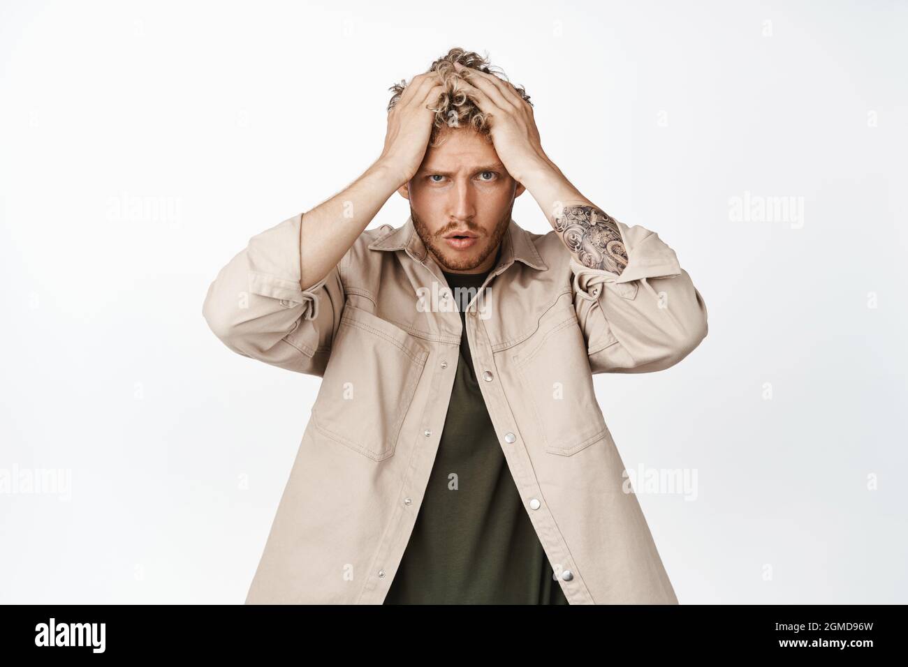 Frustrated young man in trouble, holding hands on head, looking ...