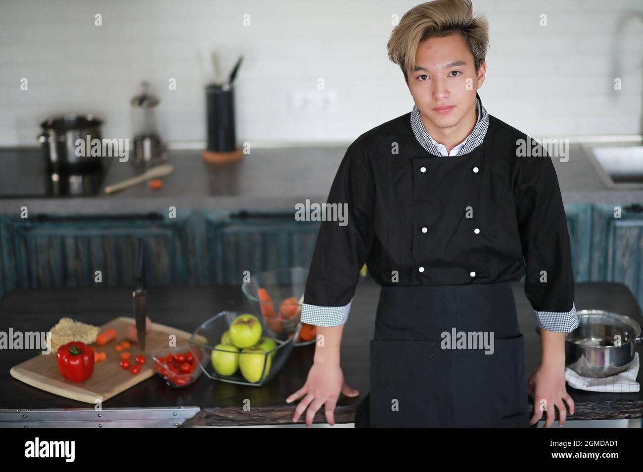 A young Asian cook in the kitchen prepares food in a cook suit Stock ...