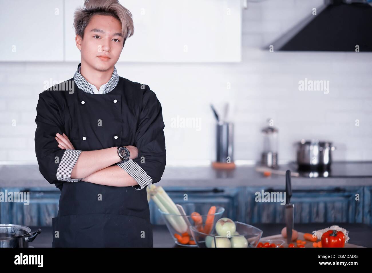A young Asian cook in the kitchen prepares food in a cook suit Stock ...