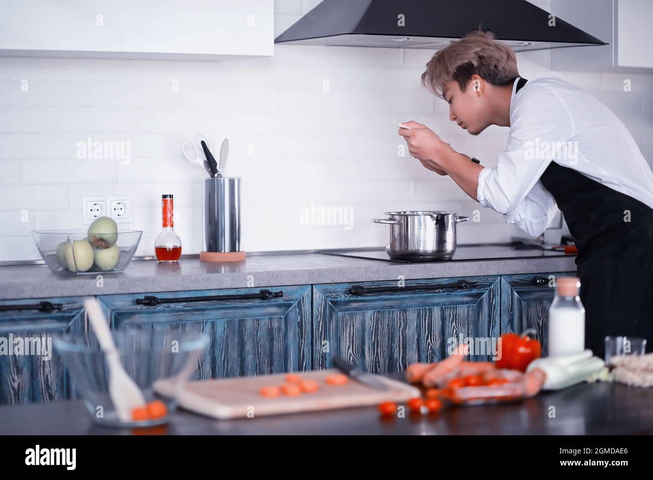A young Asian cook in the kitchen prepares food in a cook suit Stock ...
