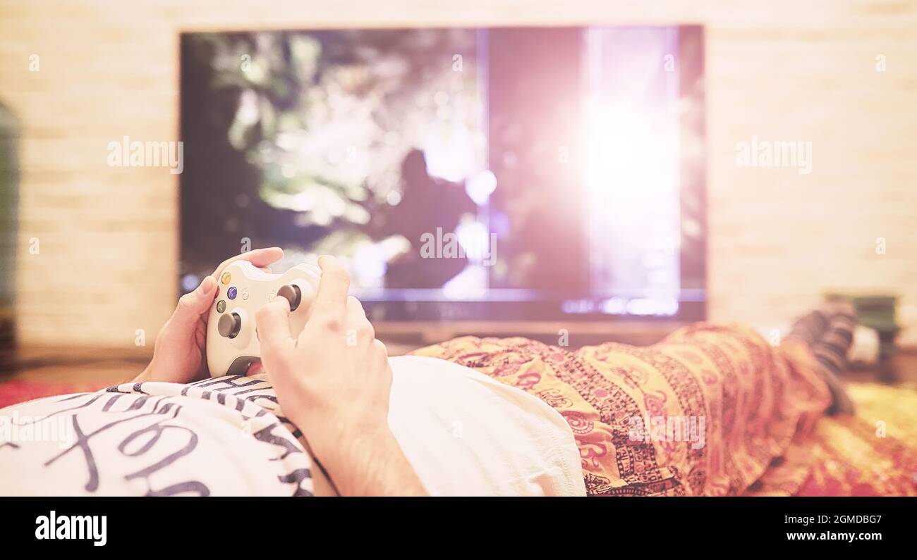 Playing on the console. Man is playing a game while lying on the floor ...