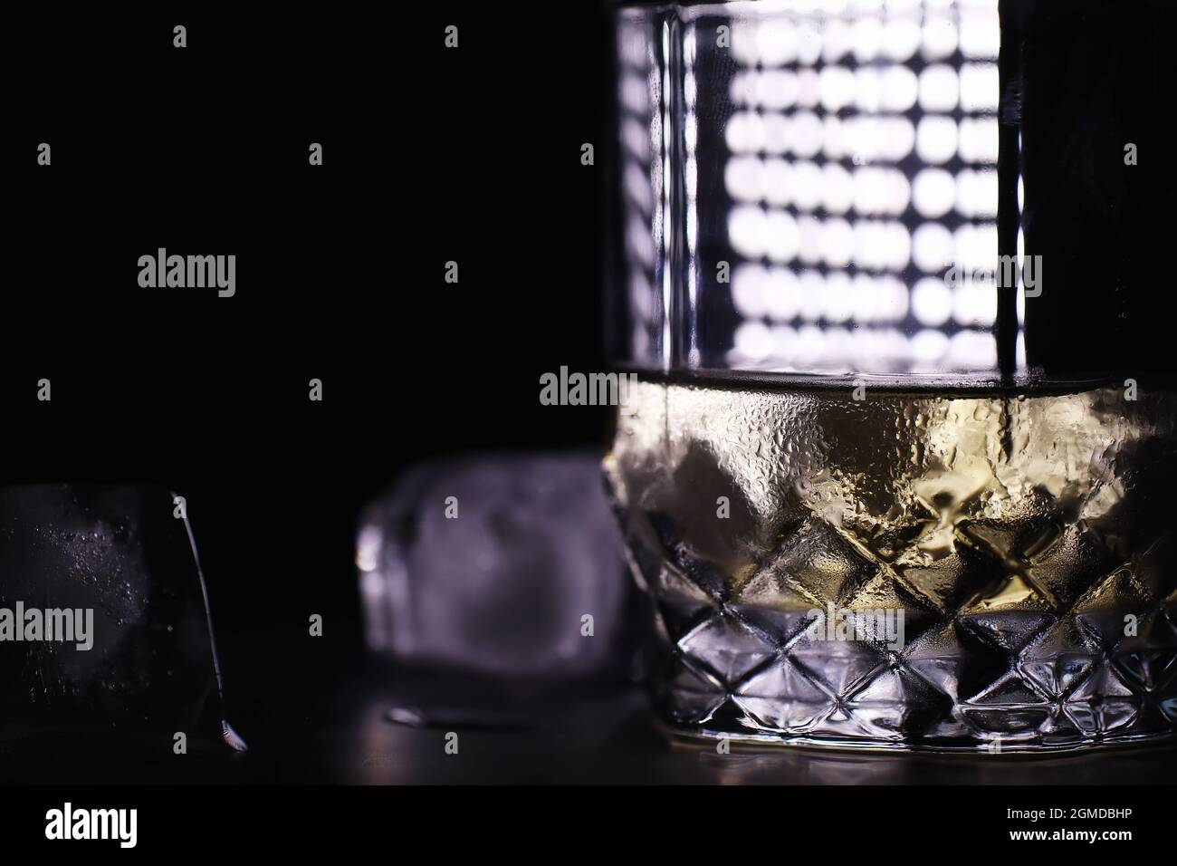 A glass of hard alcohol with ice on a bar counter. Whiskey with soda in ...