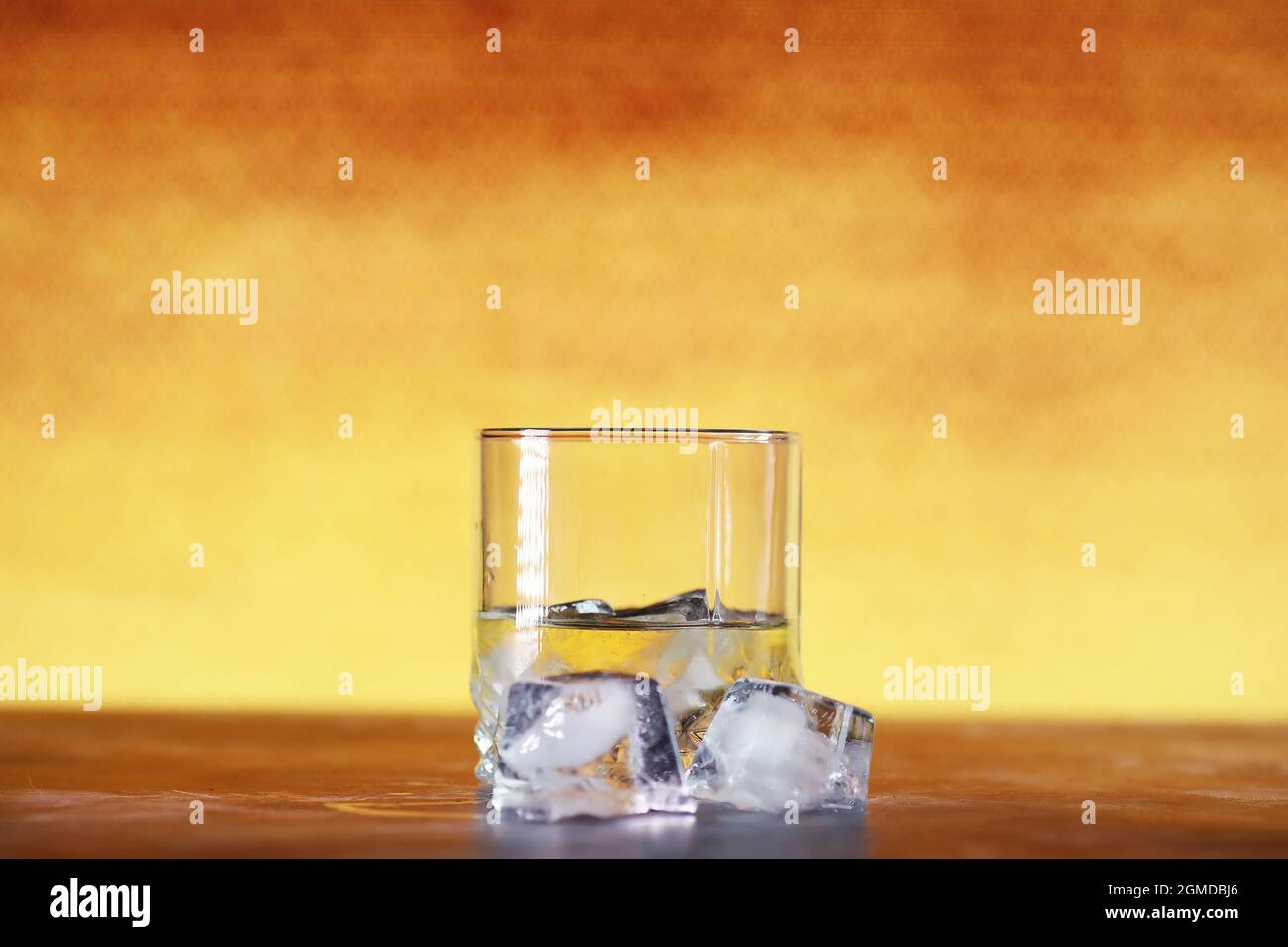 A glass of hard alcohol with ice on a bar counter. Whiskey with soda in ...