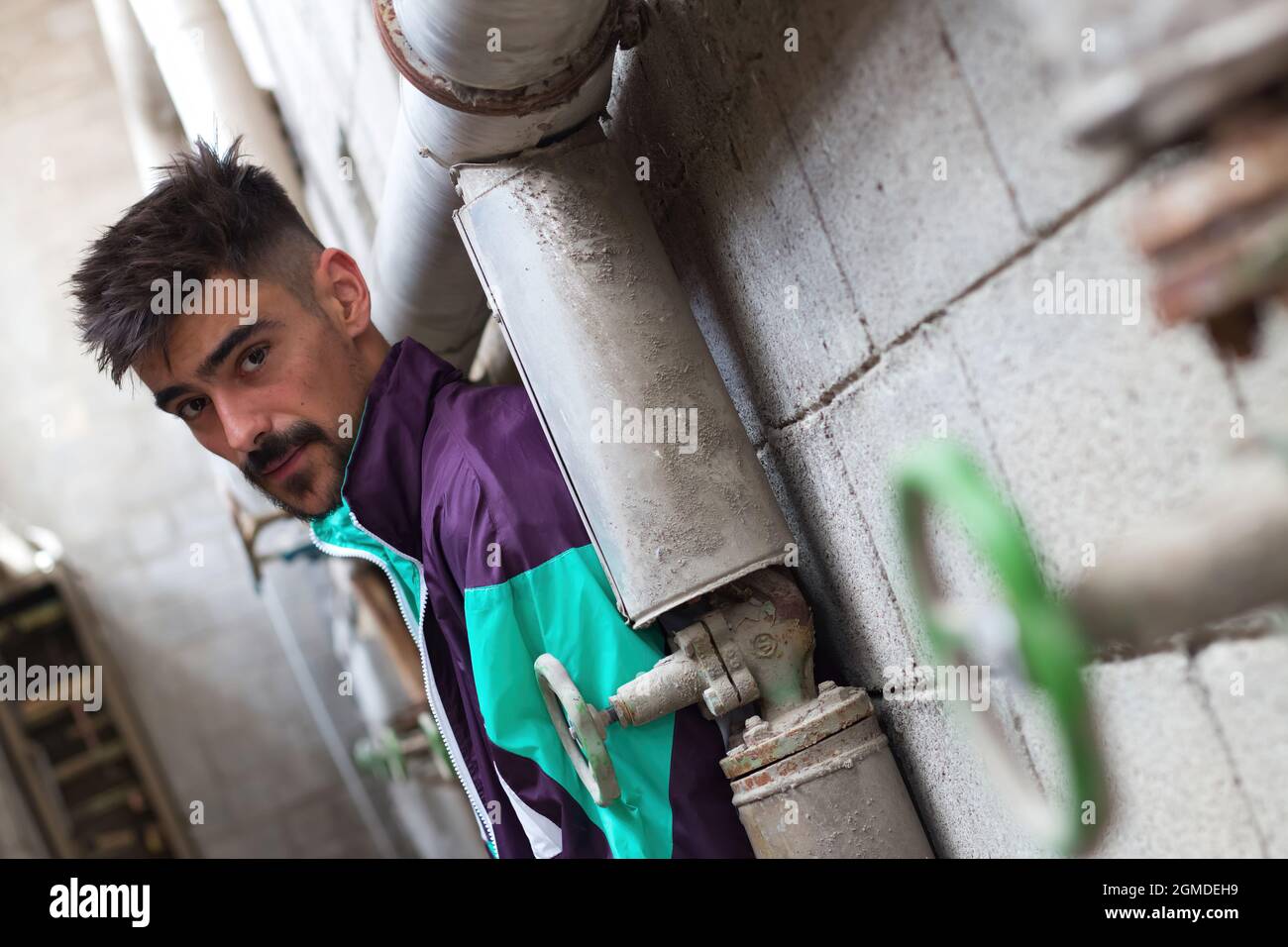 Handsome young man between old pipes Stock Photo - Alamy