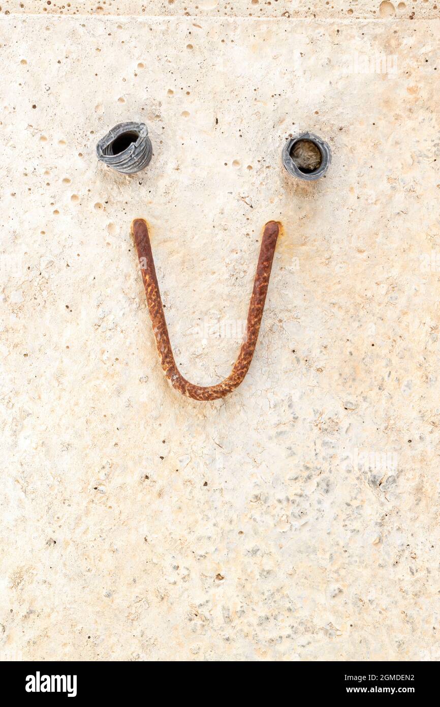 Concrete block and iron handles reminiscent of a smiling human face ...