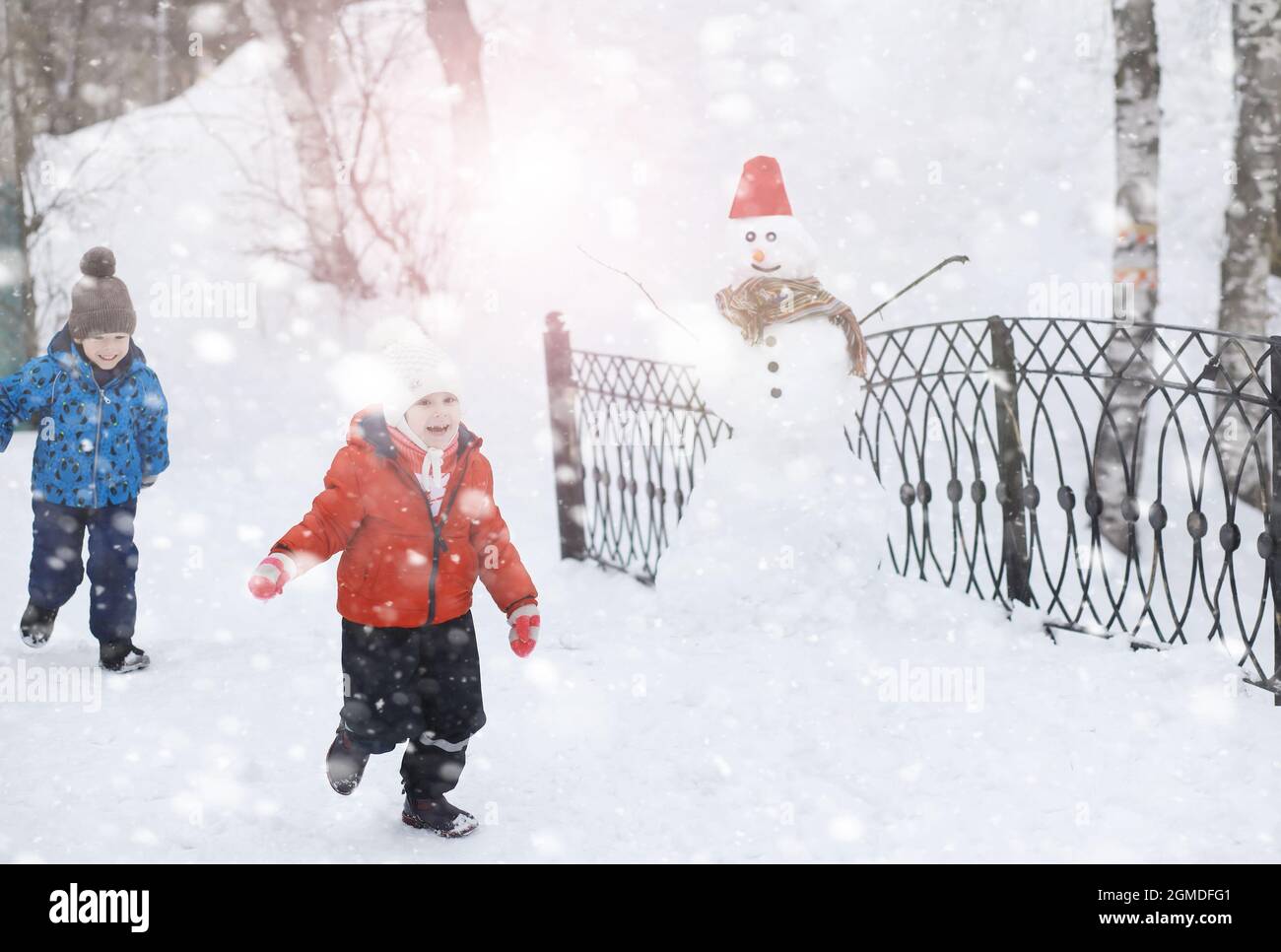 Children in the park in winter. Kids play with snow on the playground ...
