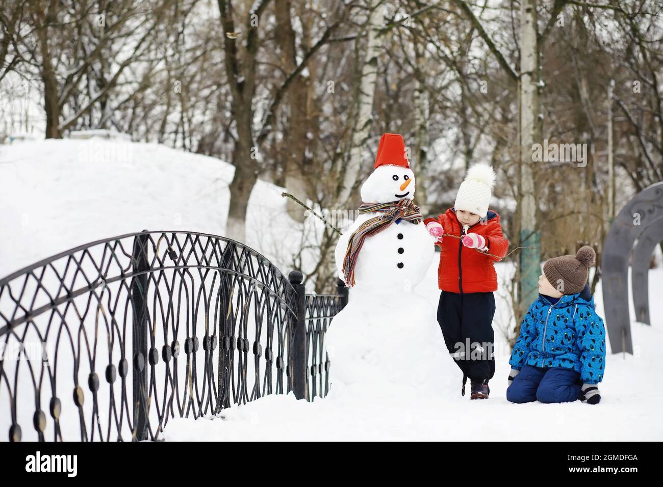 Children in the park in winter. Kids play with snow on the playground ...