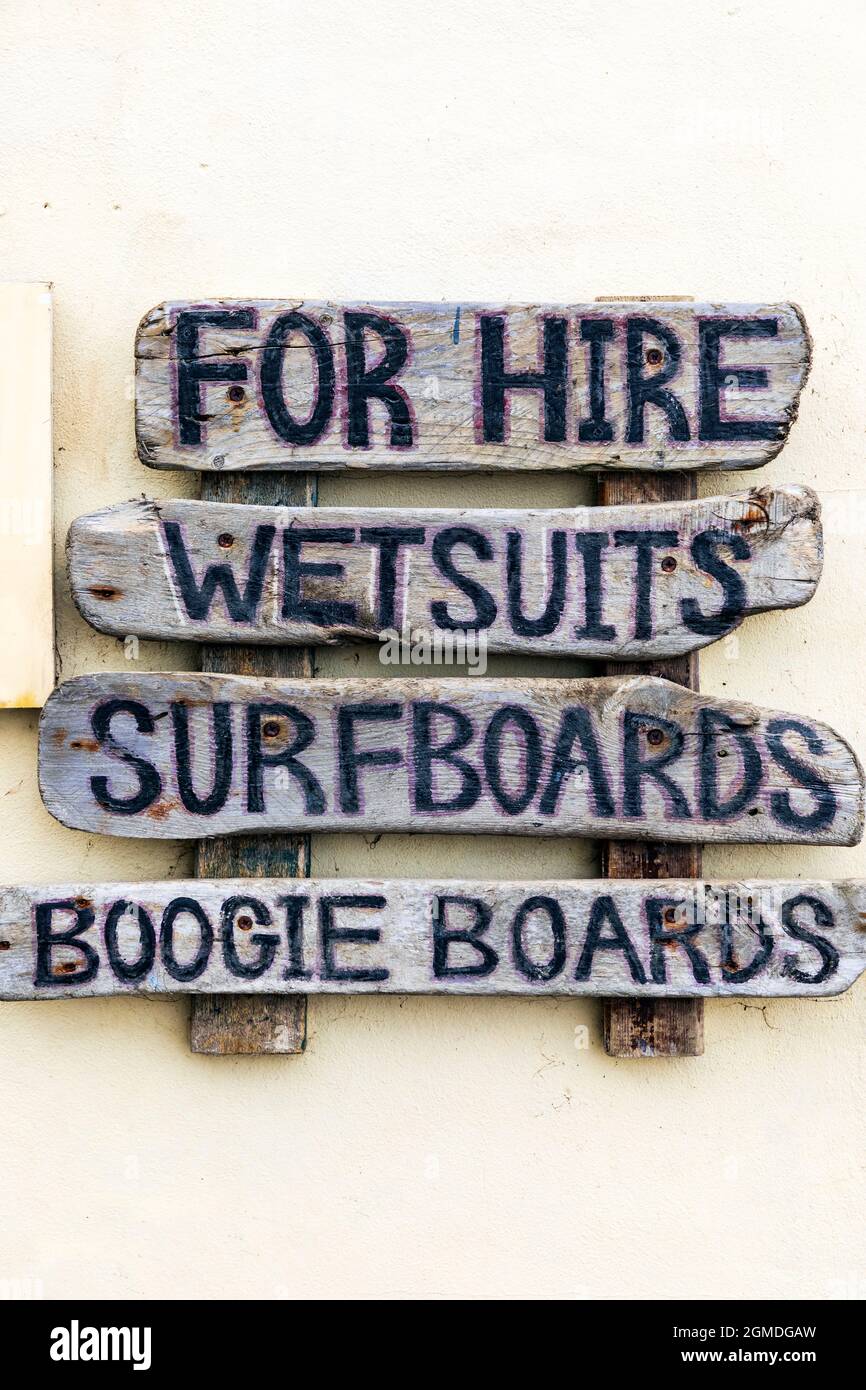 Wooden and worn sign for wetsuits, surf boards and boogie boards on a ...