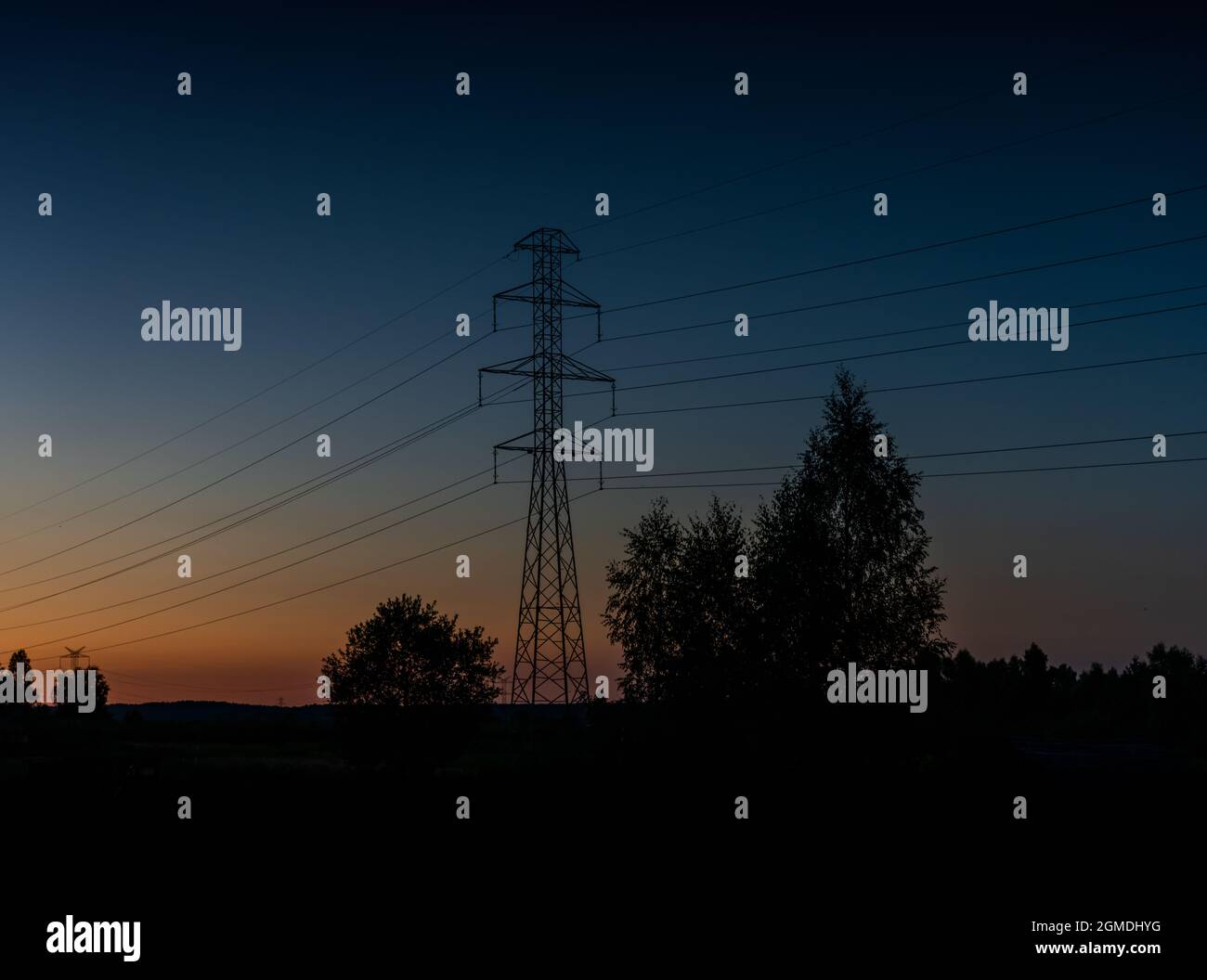 View of a lattice cross pylon and high voltage power lines at sunset ...
