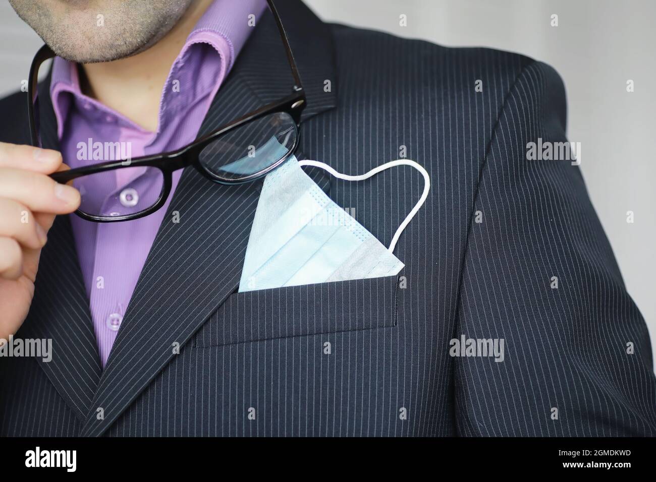 A disposable medical mask sticks out of a pocket instead napkin. A man ...