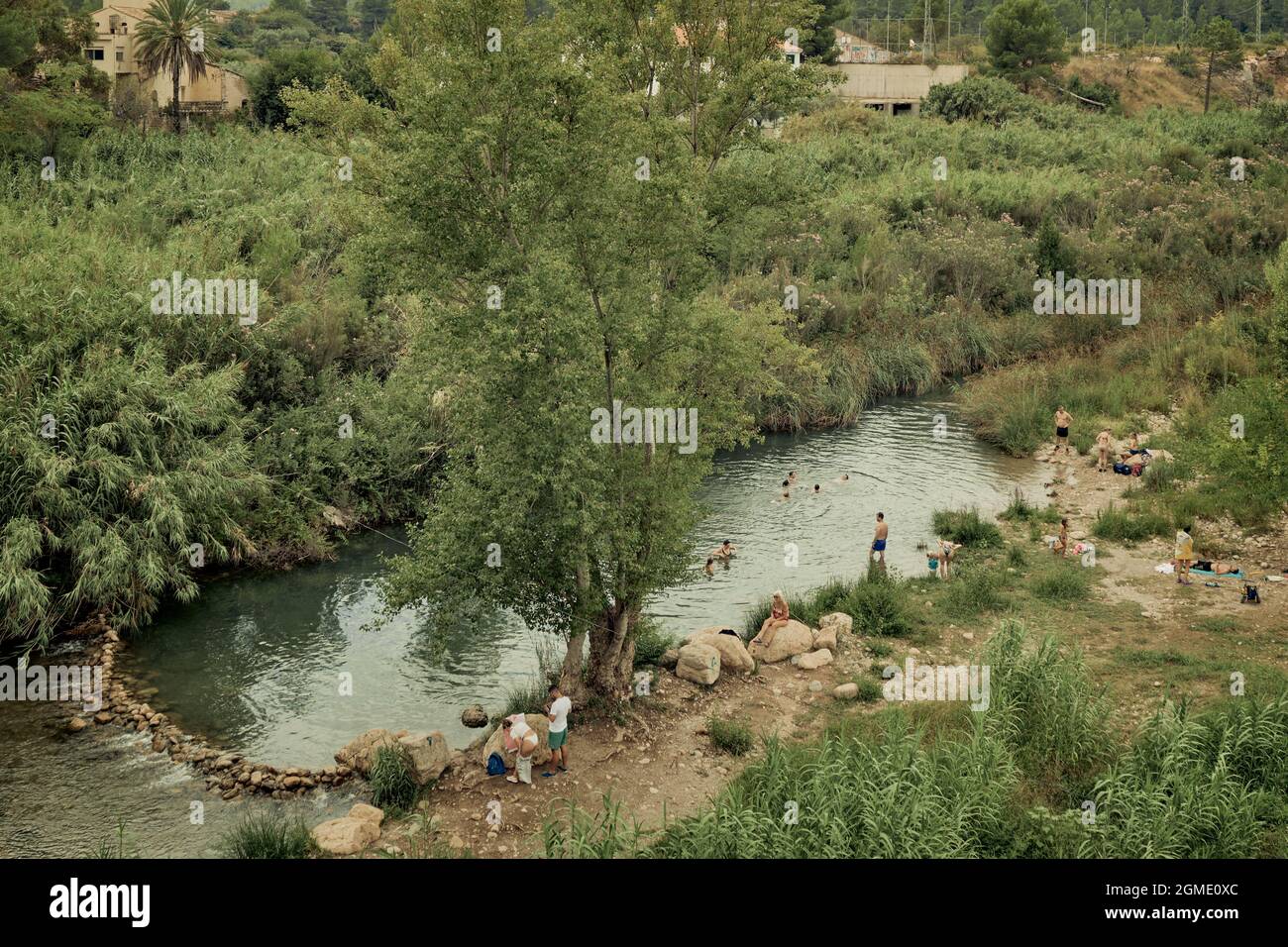 people bathing in the river Mijares on the beach of vegetation and ...