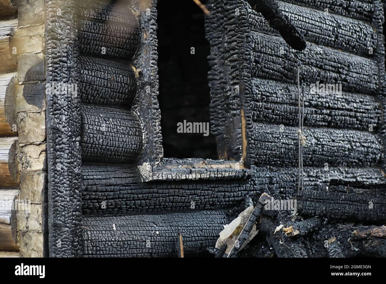 Wooden house after the fire. Coals on the logs. The ashes of the house ...