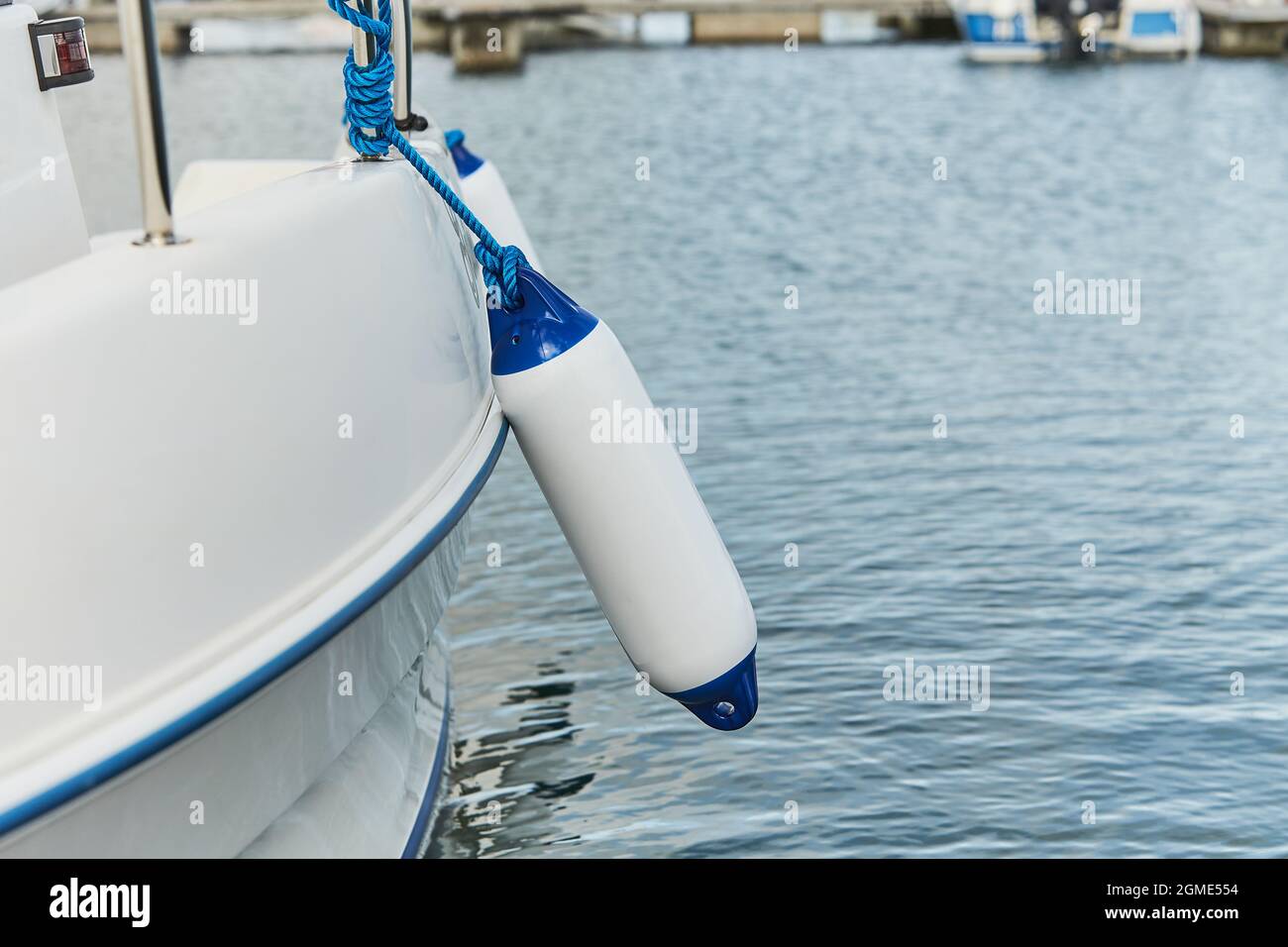 White fenders suspended between a boat and dockside for protection ...