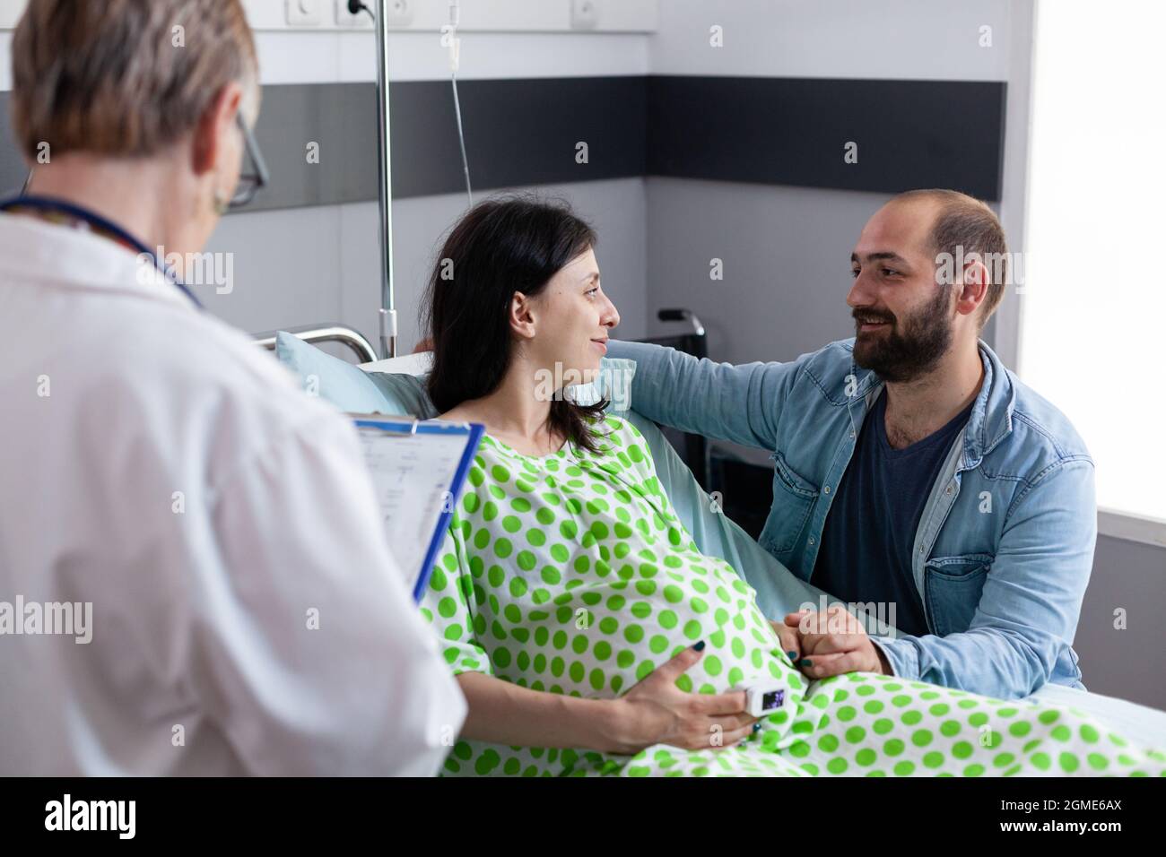 Maternity doctor examining pregnant woman sitting in hospital ward bed ...