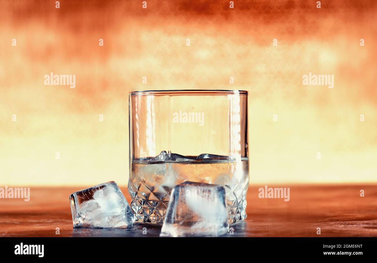 A glass of hard alcohol with ice on a bar counter. Whiskey with soda in ...
